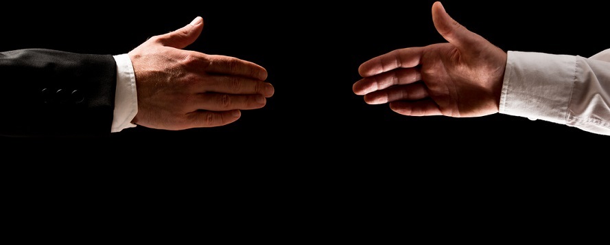 Two men reaching out to shake hands - scopexec
